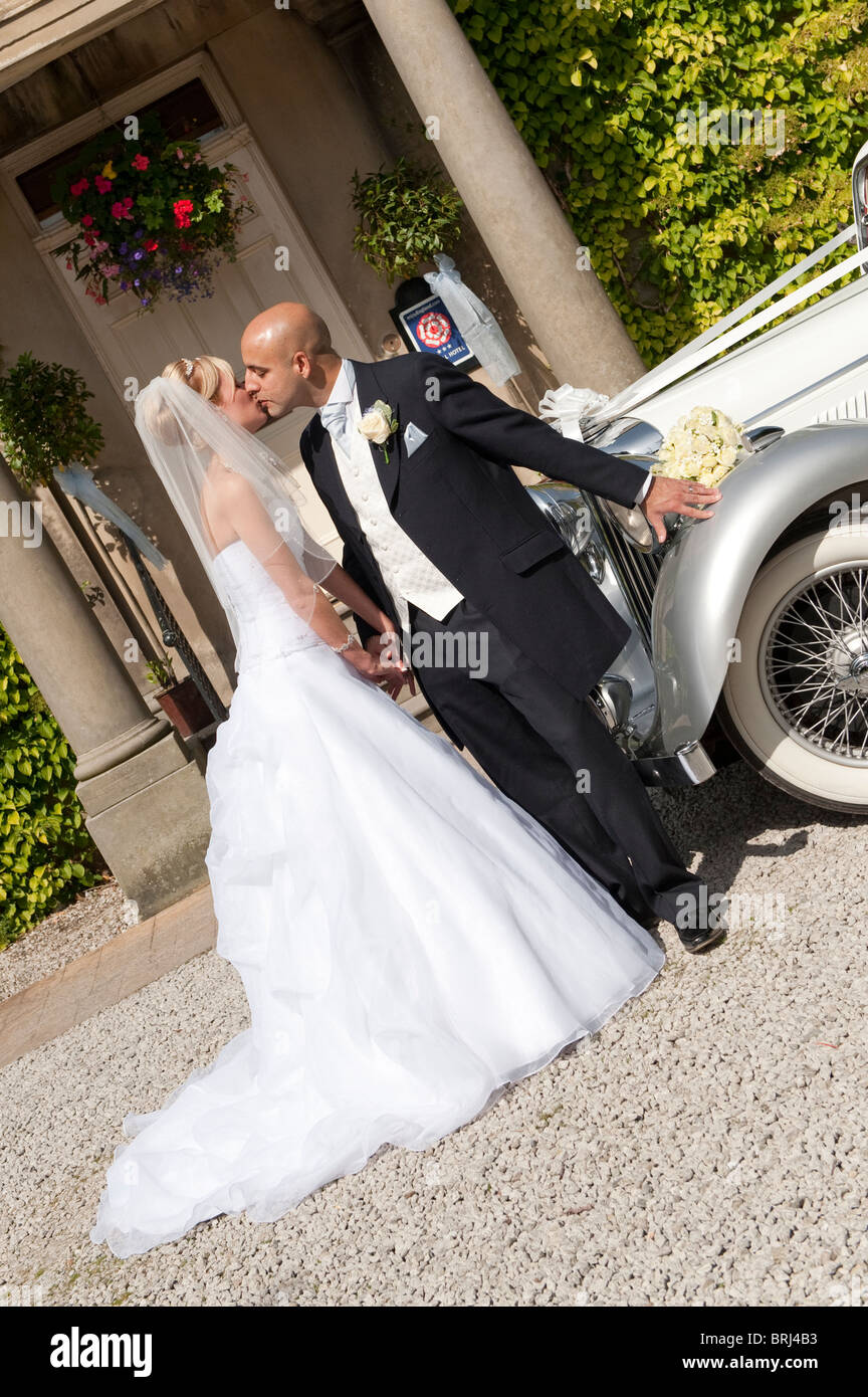A stunning looking bride and groom next to a vintage wedding car Stock ...