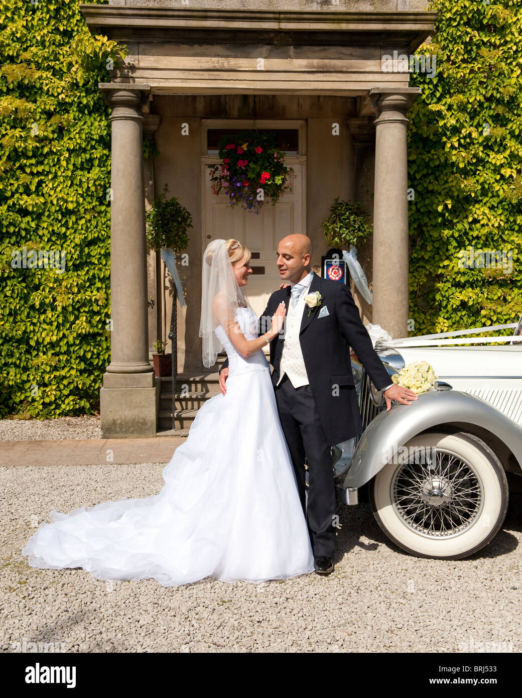 A stunning looking bride and groom next to a vintage wedding car Stock ...