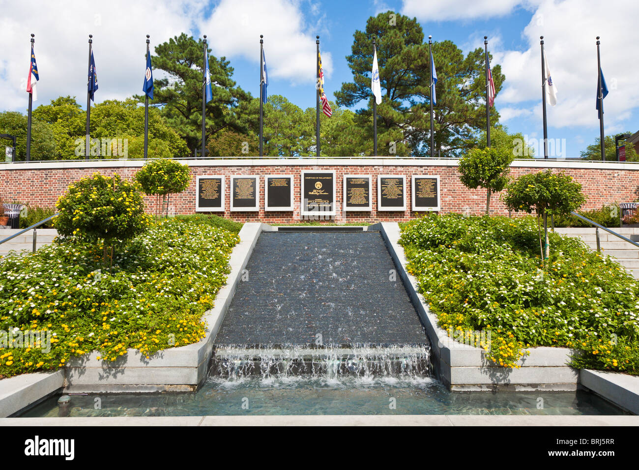Fountain with 13 colonial flags at entrance to Colonial Williamsburg, a ...