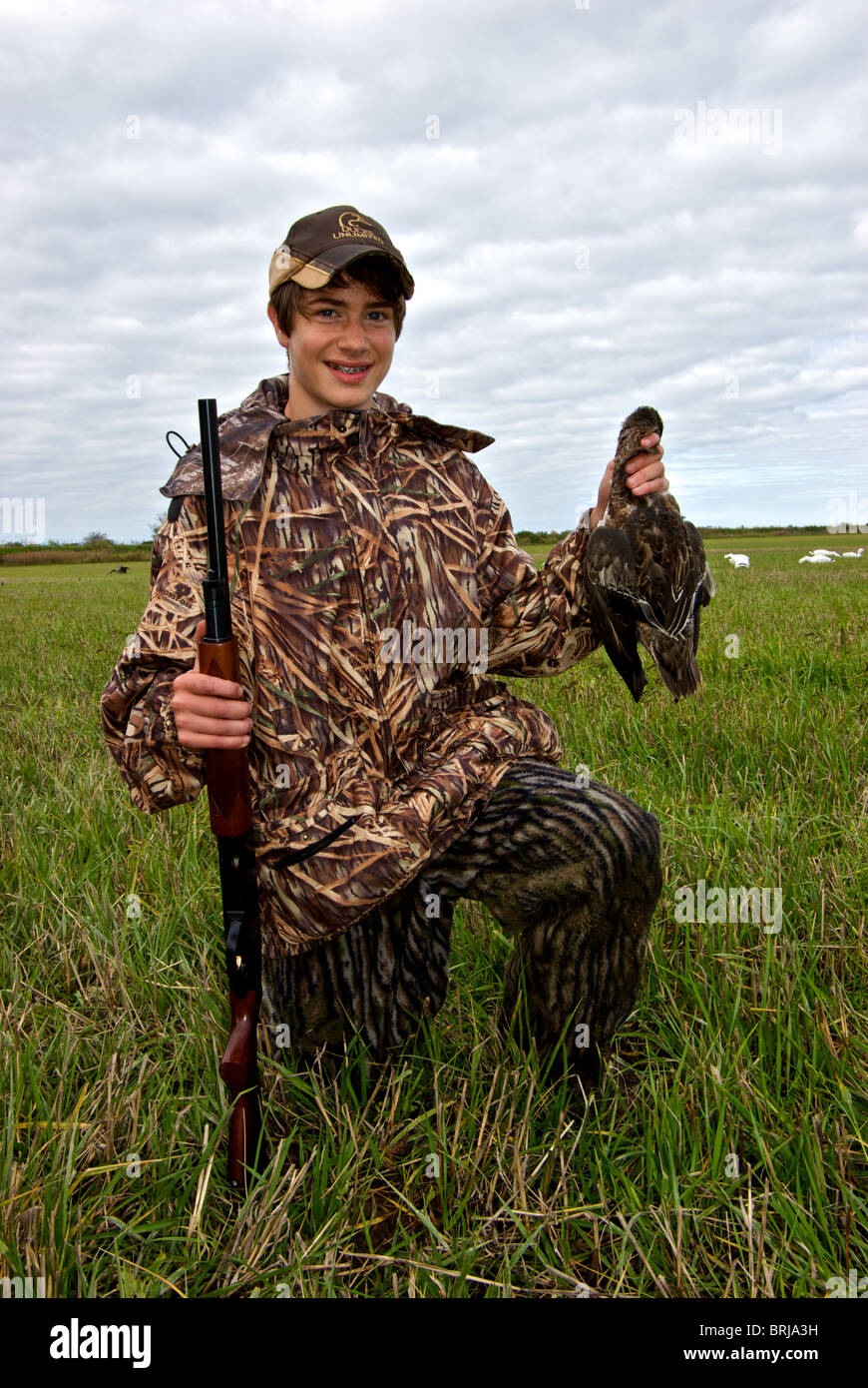 Young duck hunter wearing camouflage clothing holding dead American ...