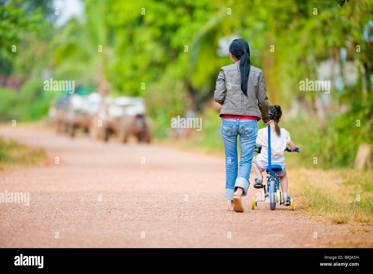 mother guiding her daughter on a bike Stock Photo - Alamy