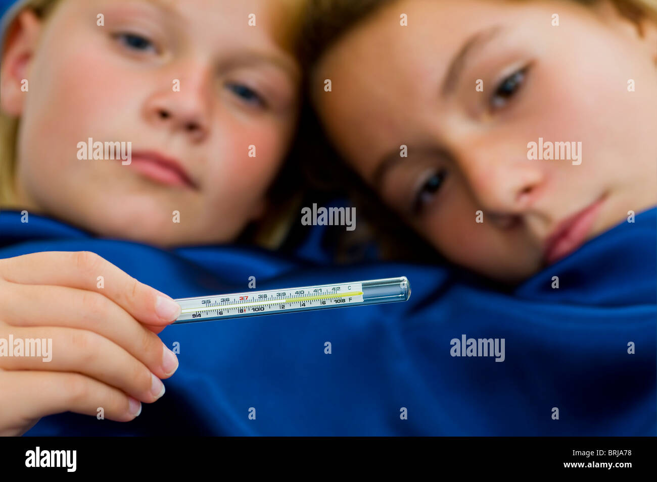 two girls sick in bed, having over 39?C /102?F fever. focus on ...