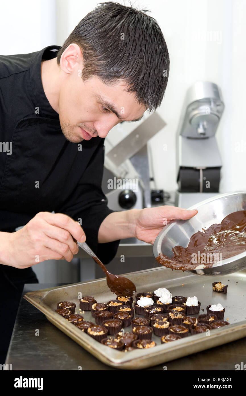 caucasian male chef makes chocolate sweets according to his own recipe ...