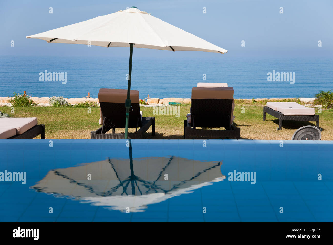 Parasol reflecting in swimming pool overlooking the Mediterranean Sea ...