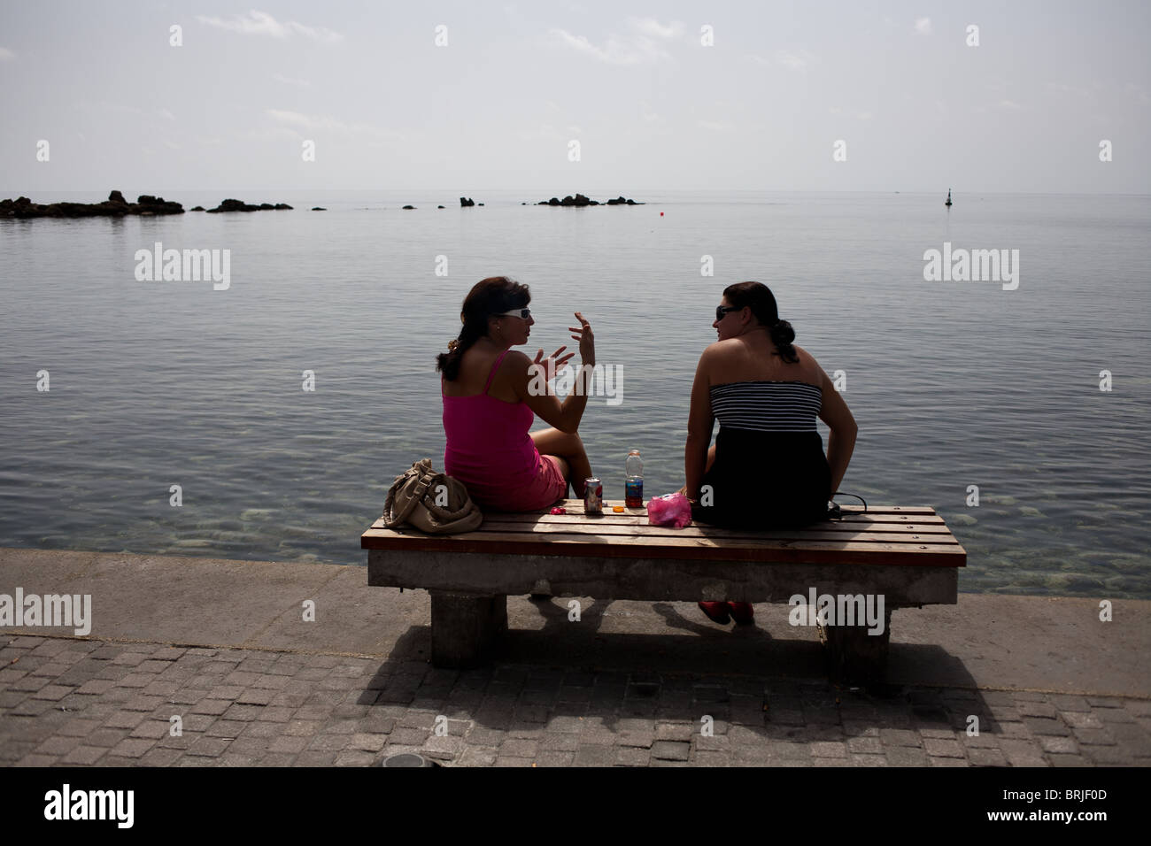 Two women on bench overlooking Paphos Harbor Stock Photo - Alamy