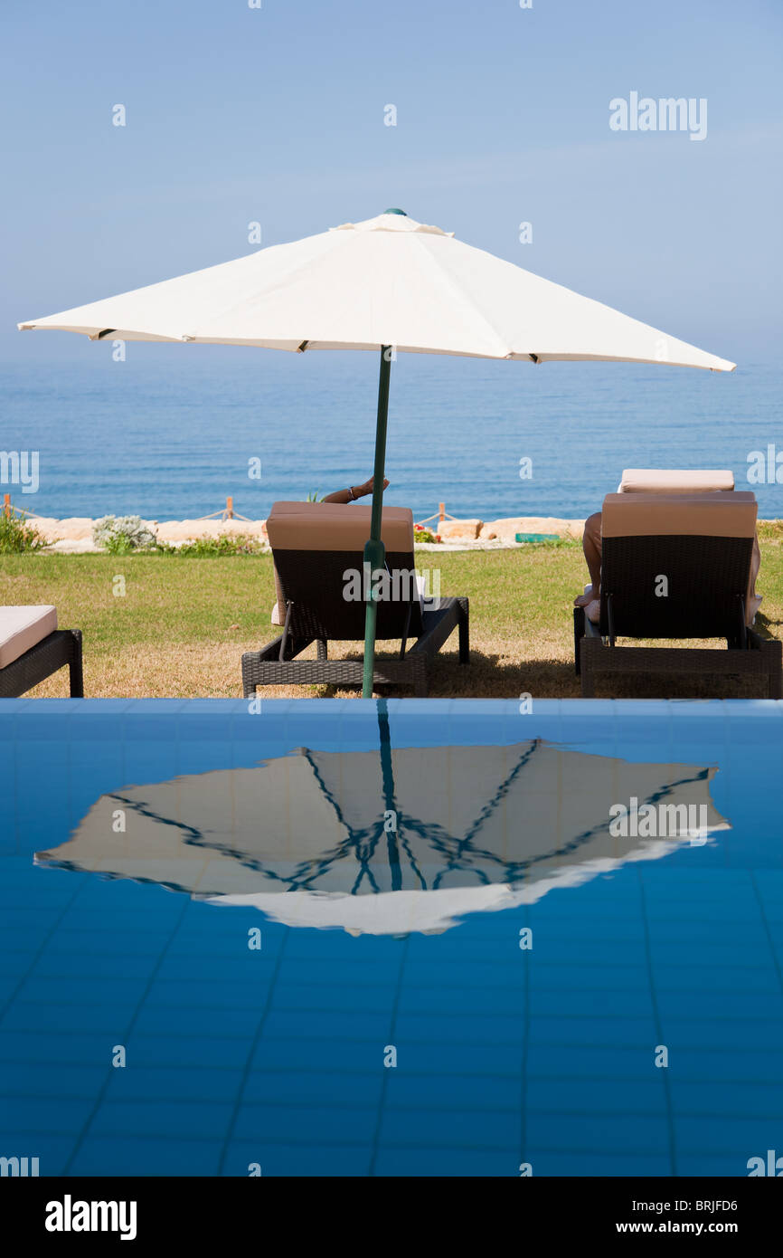 Parasol reflecting in swimming pool overlooking the Mediterranean Sea ...
