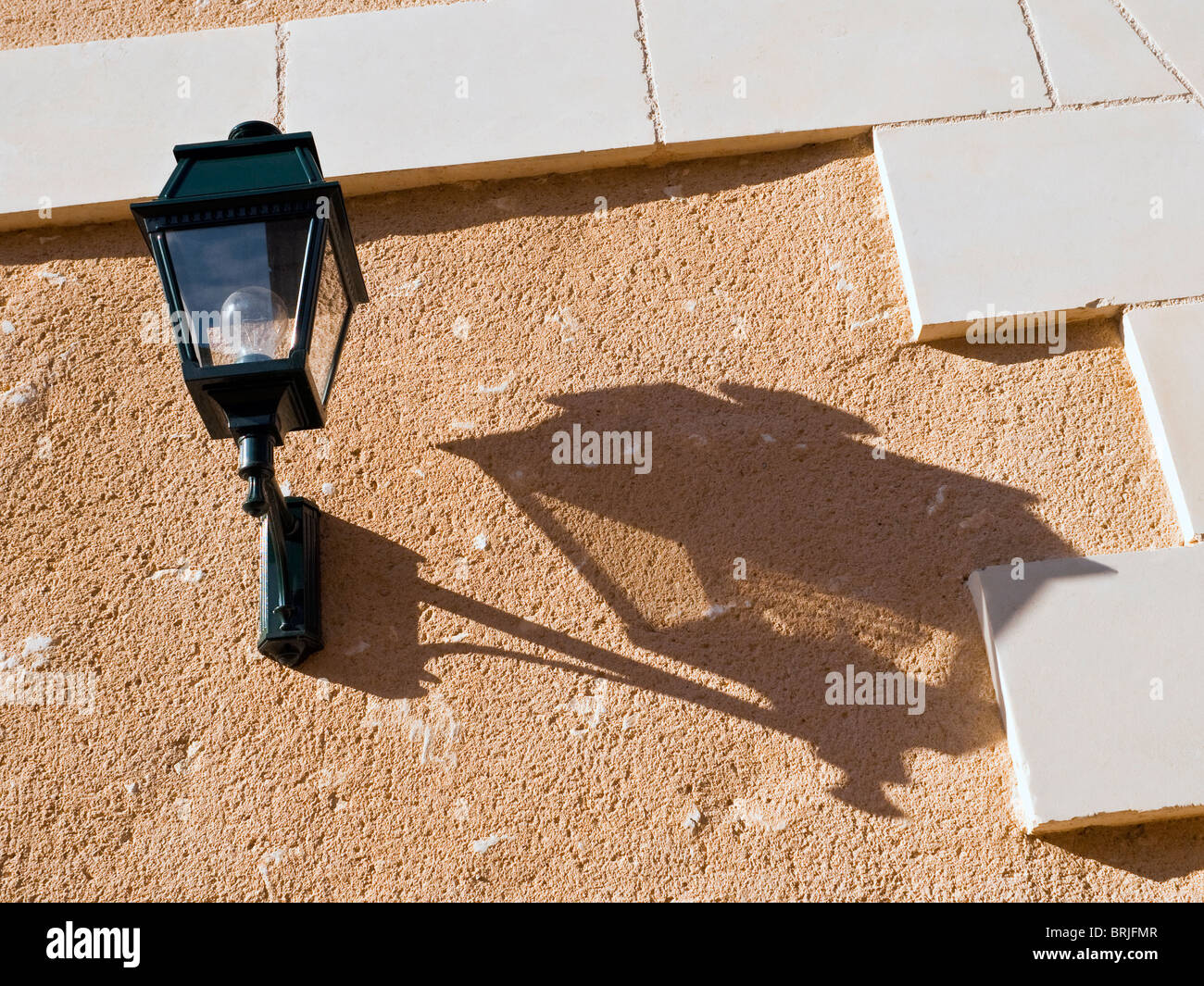 Outdoor lamp casting shadow on house wall - France Stock Photo - Alamy