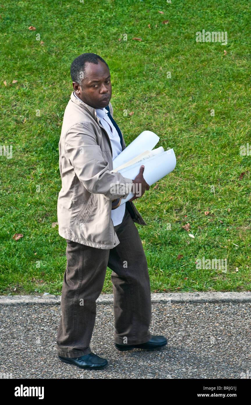 Overhead view of black man walking along pavement carrying papers ...