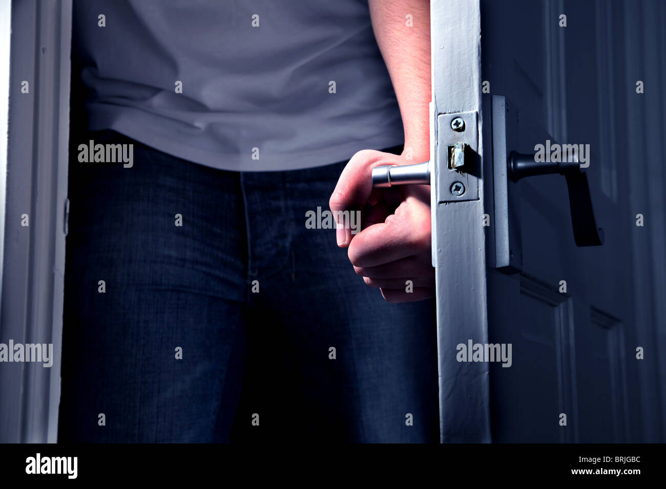 Caucasian hand turning the handle opening a door and entering a dark ...