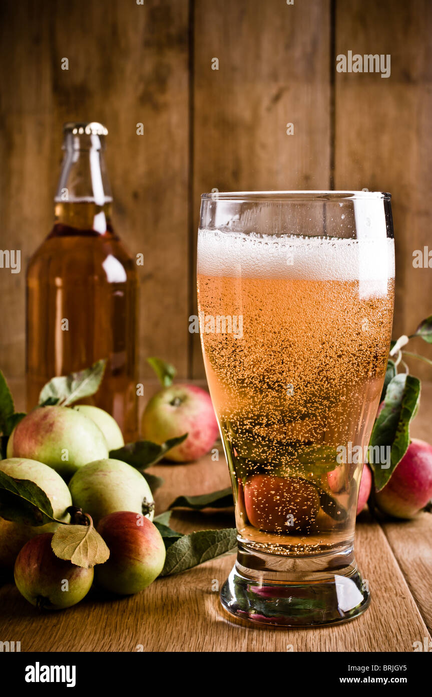 Glass of cider with apples and bottle on rustic wooden background Stock ...