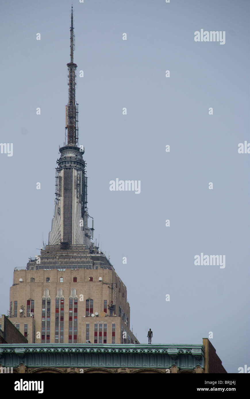 Top of Empire State Building with sculpture of man standing on the edge ...