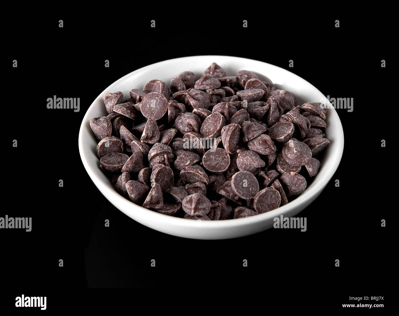 closeup macro of a cooking ingredient - milk chocolate chips in a white ...