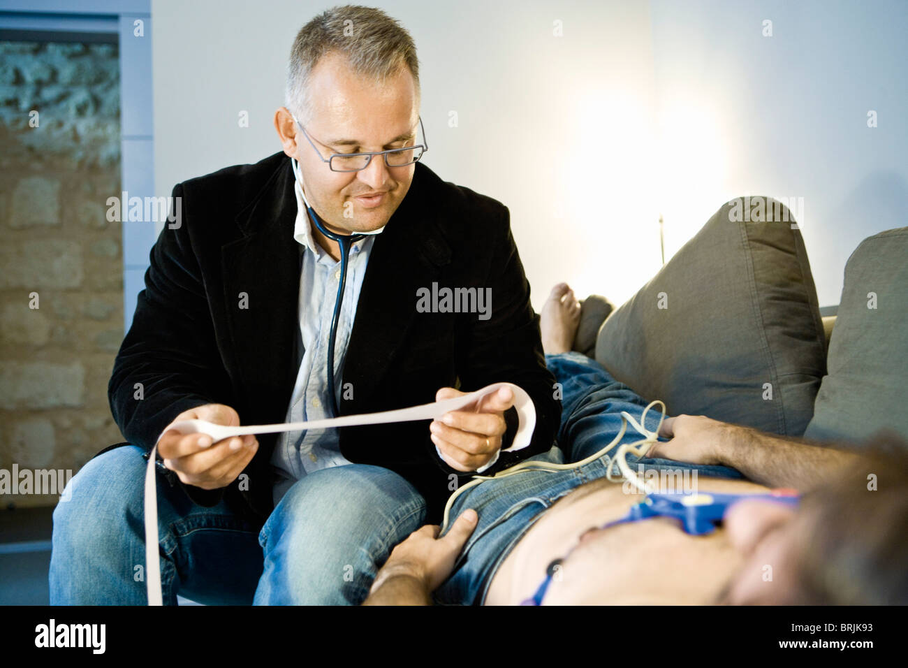 Doctor performing portable EKG (electrocardiogram) on patient in home ...