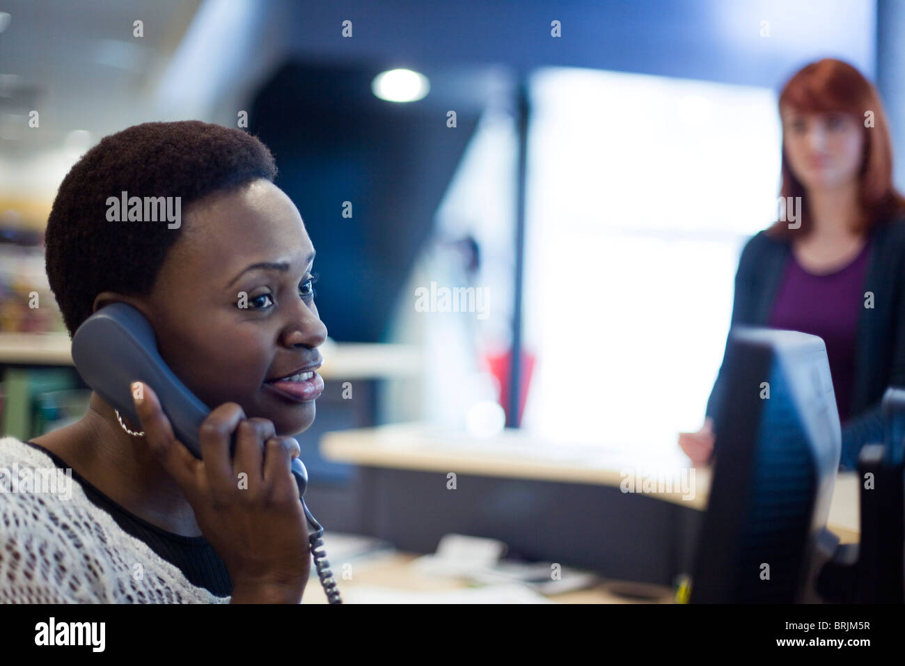 Female receptionist talking on phone Stock Photo - Alamy