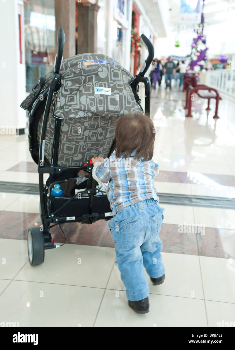 Baby Boy Pushing Stroller in Shopping Mall Stock Photo - Alamy