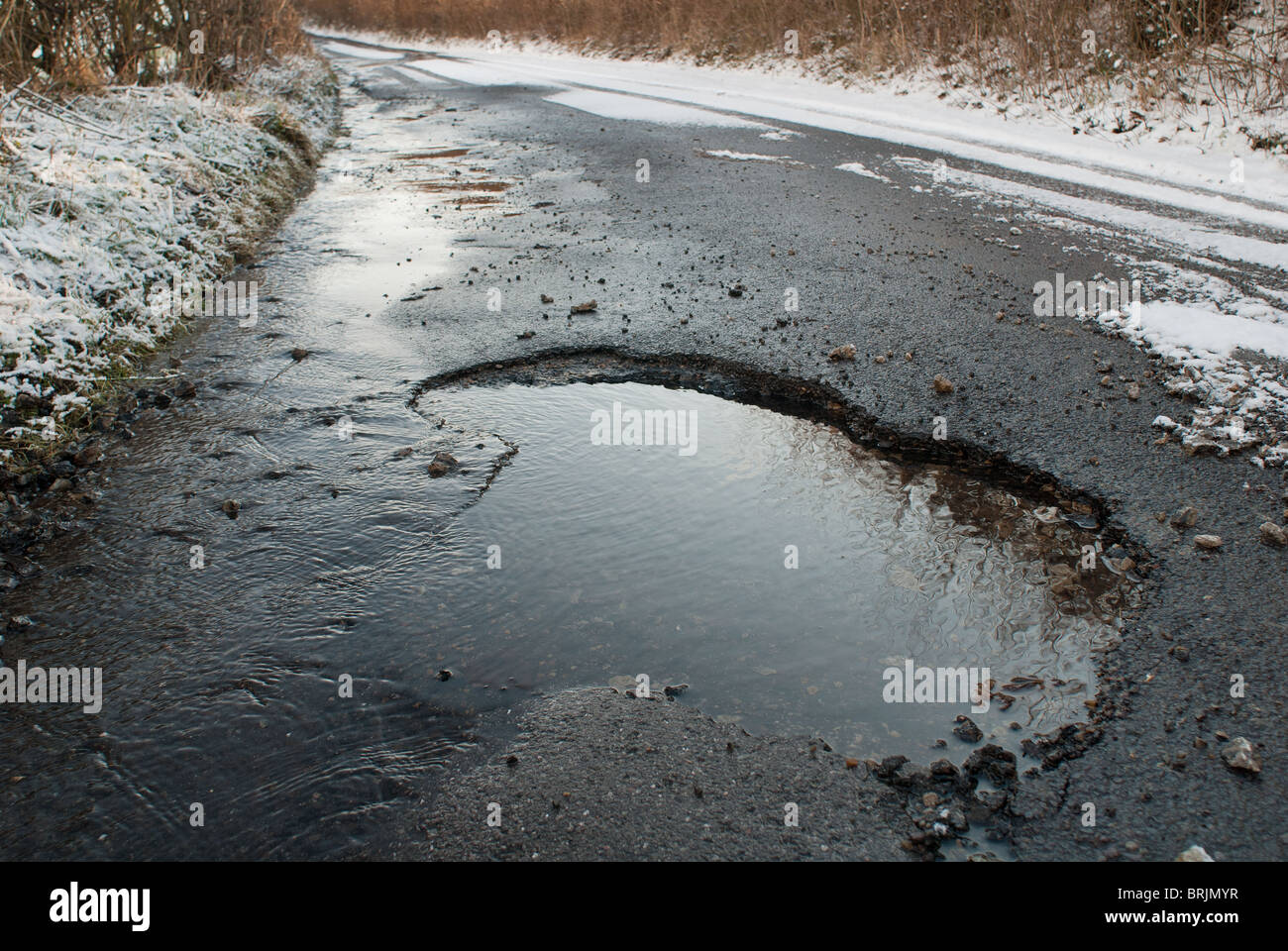 Potholes in a country road caused by snow and freezing weather melting ...