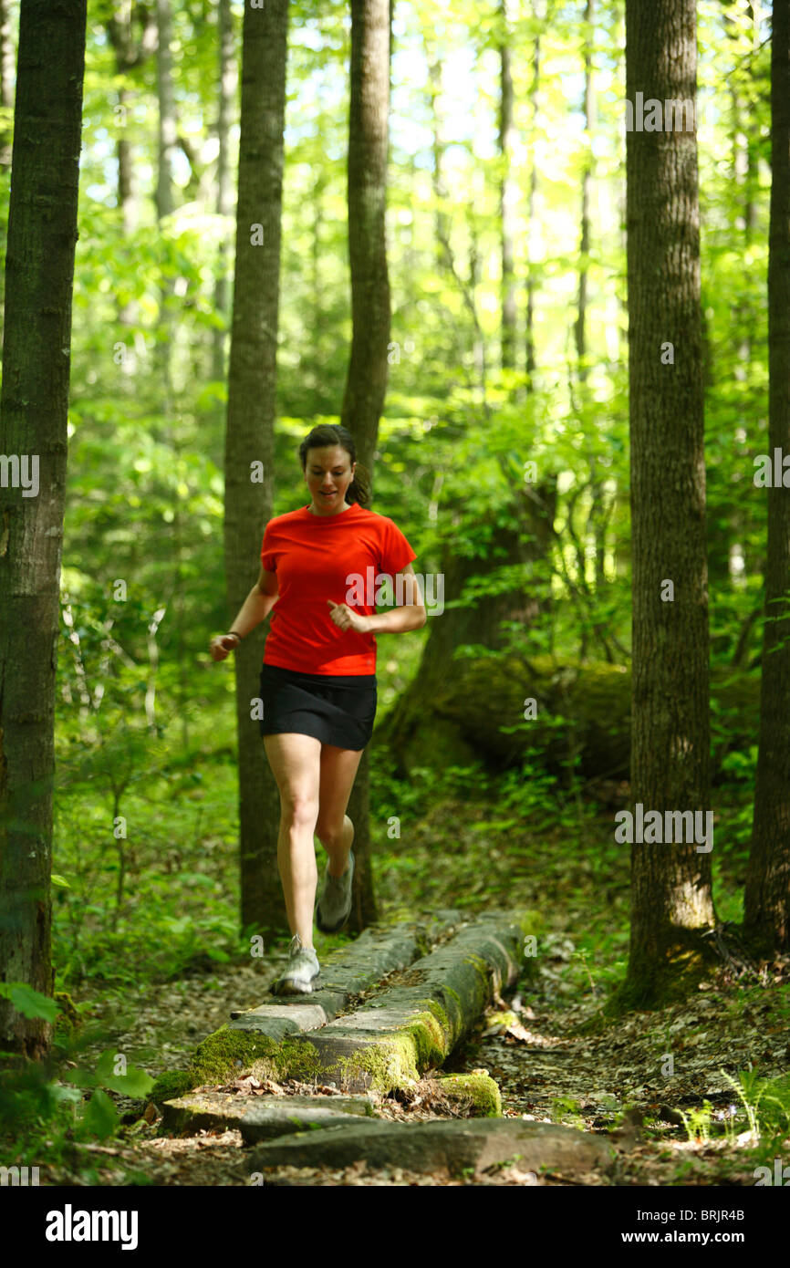 Woman trail running in a lush green forest Stock Photo - Alamy