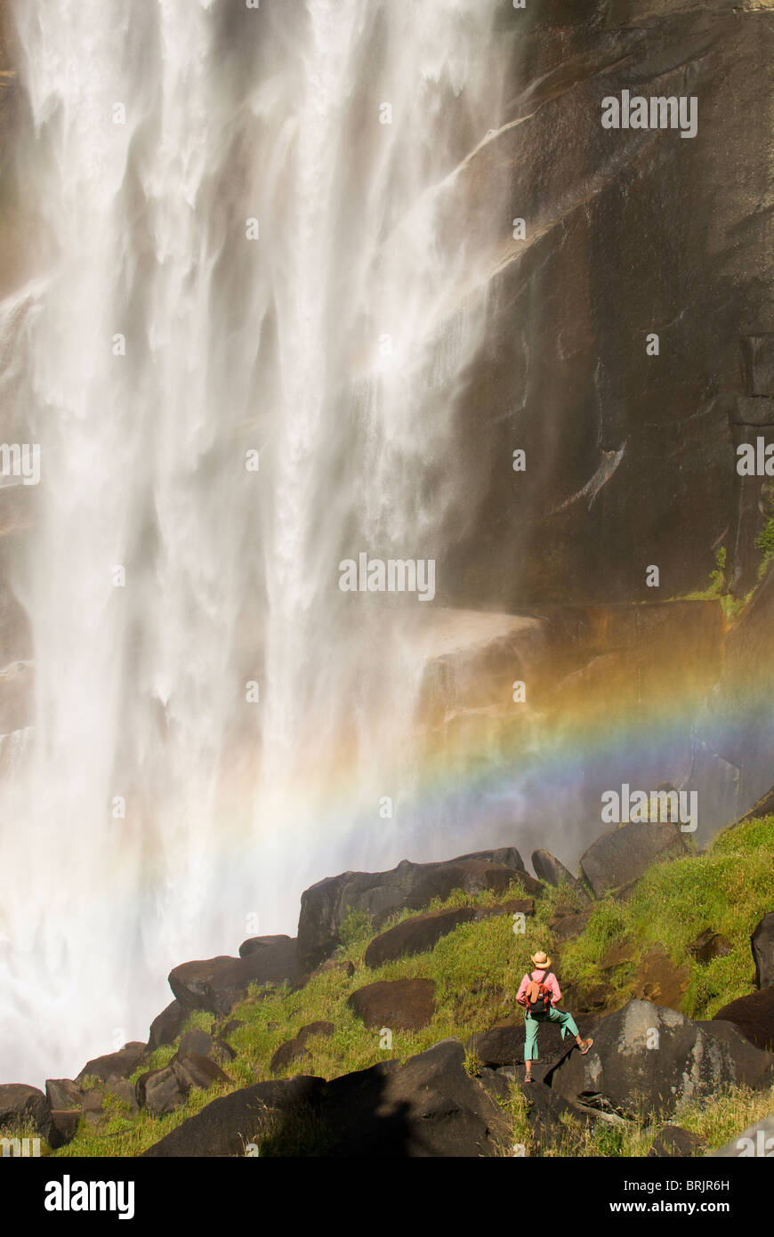 A young woman explores beneath a giant waterfall Stock Photo - Alamy