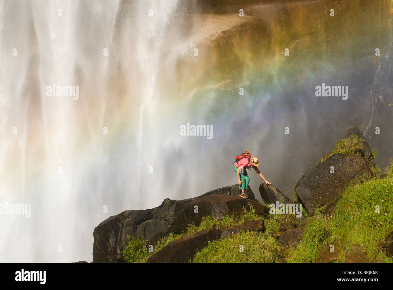 A young woman explores beneath a giant waterfall Stock Photo - Alamy