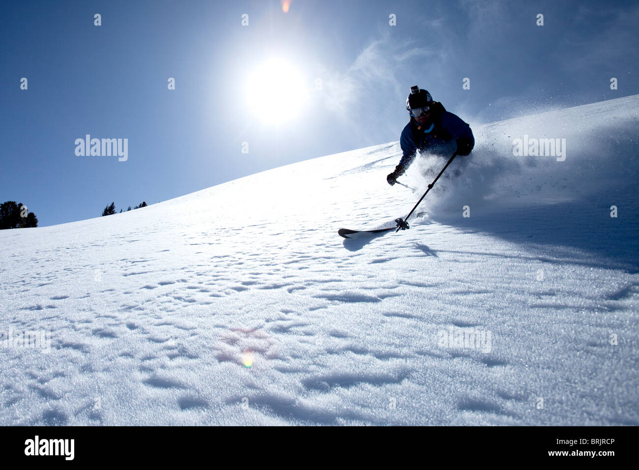 Low angle perspective of one man telemark skiing on a blue sky day ...