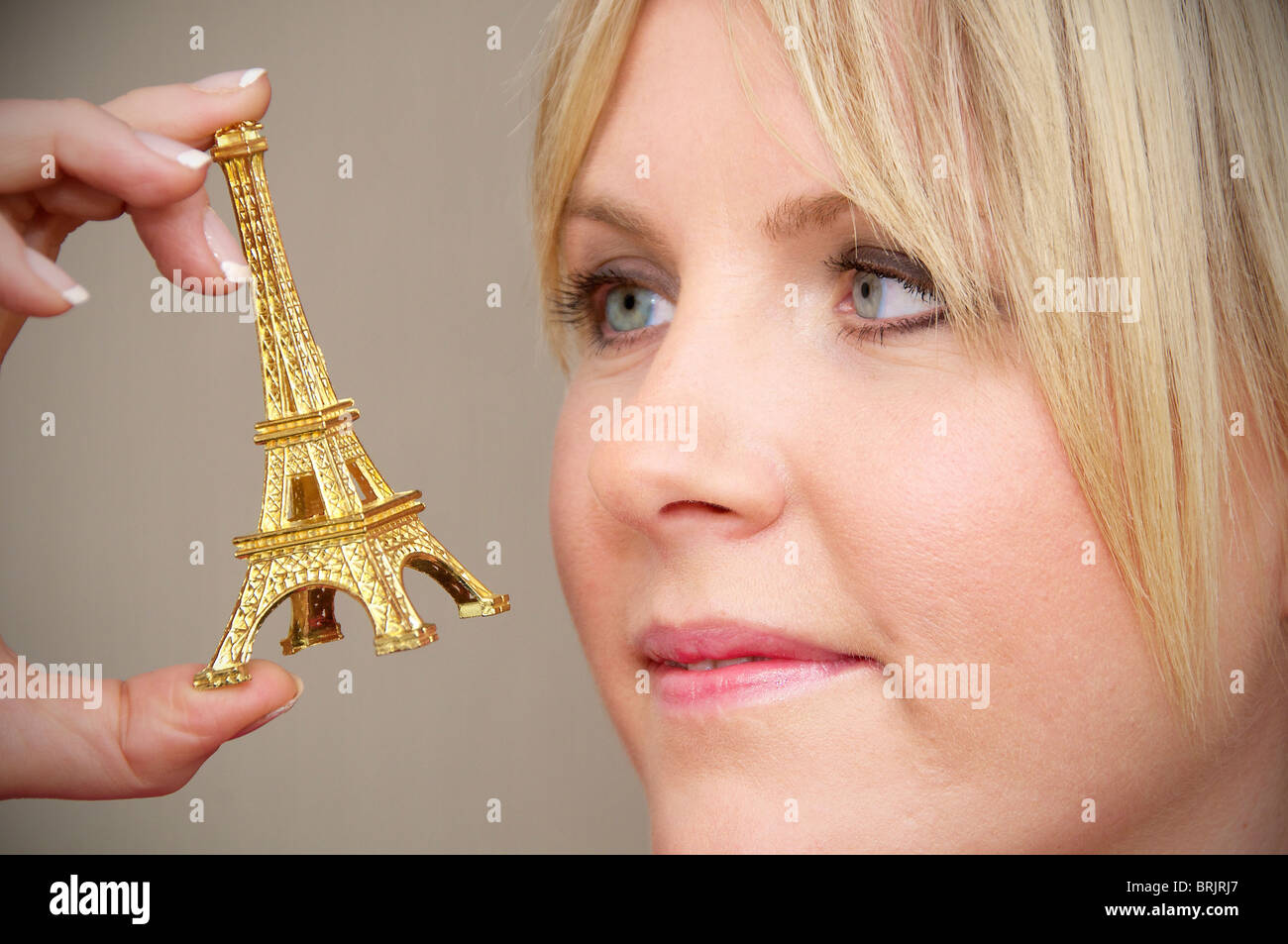 A young girl with a souvenir model in gold metal showing the Eiffel ...
