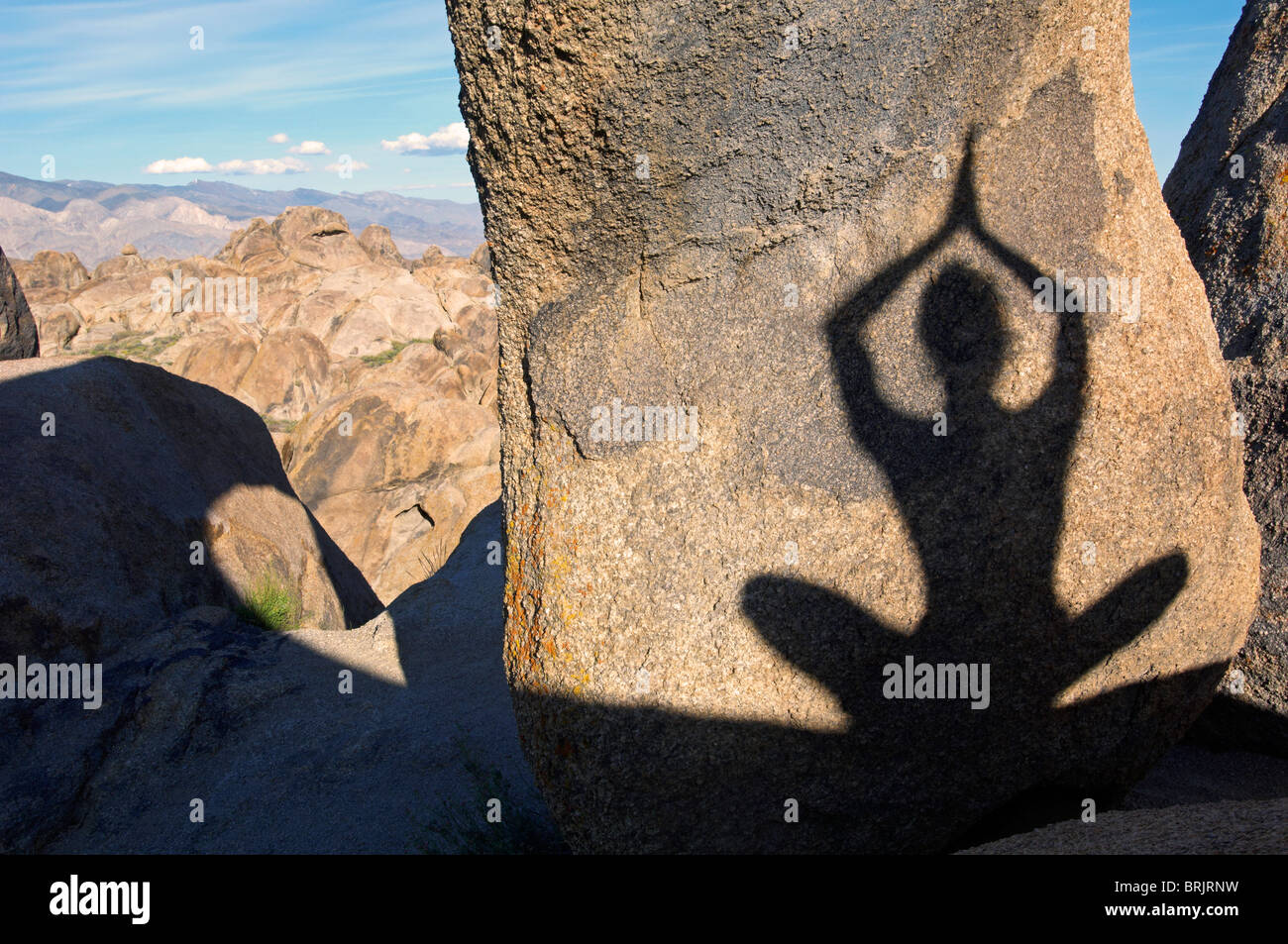 A shadow on a boulder of a woman practicing yoga Stock Photo - Alamy