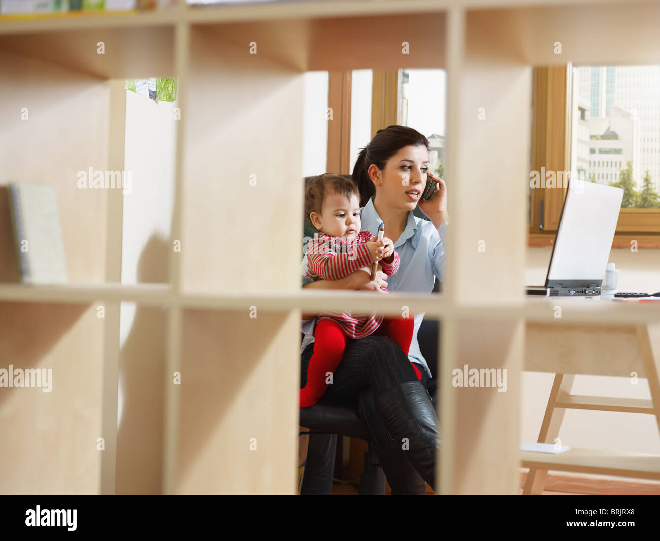 multitasking businesswoman holding her baby and talking on mobile phone ...