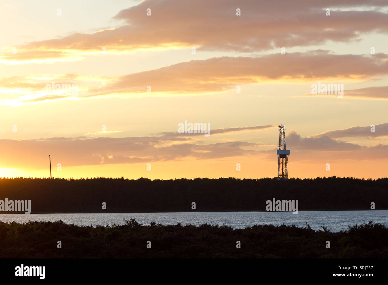 The sun sets behind Wytch Farm oil field in Poole Harbour. Dorset, UK ...