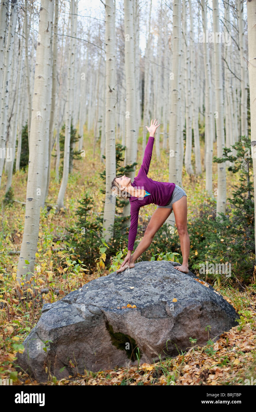 A young woman performs a yoga pose on a rock in Big Cottonwood Canyon ...