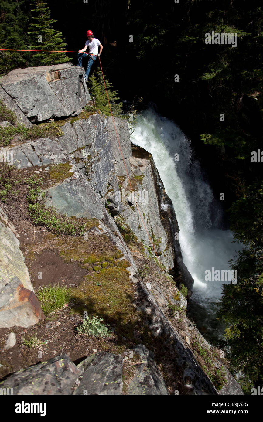 A young man rappels down a cliff next to a waterfall in Idaho Stock ...
