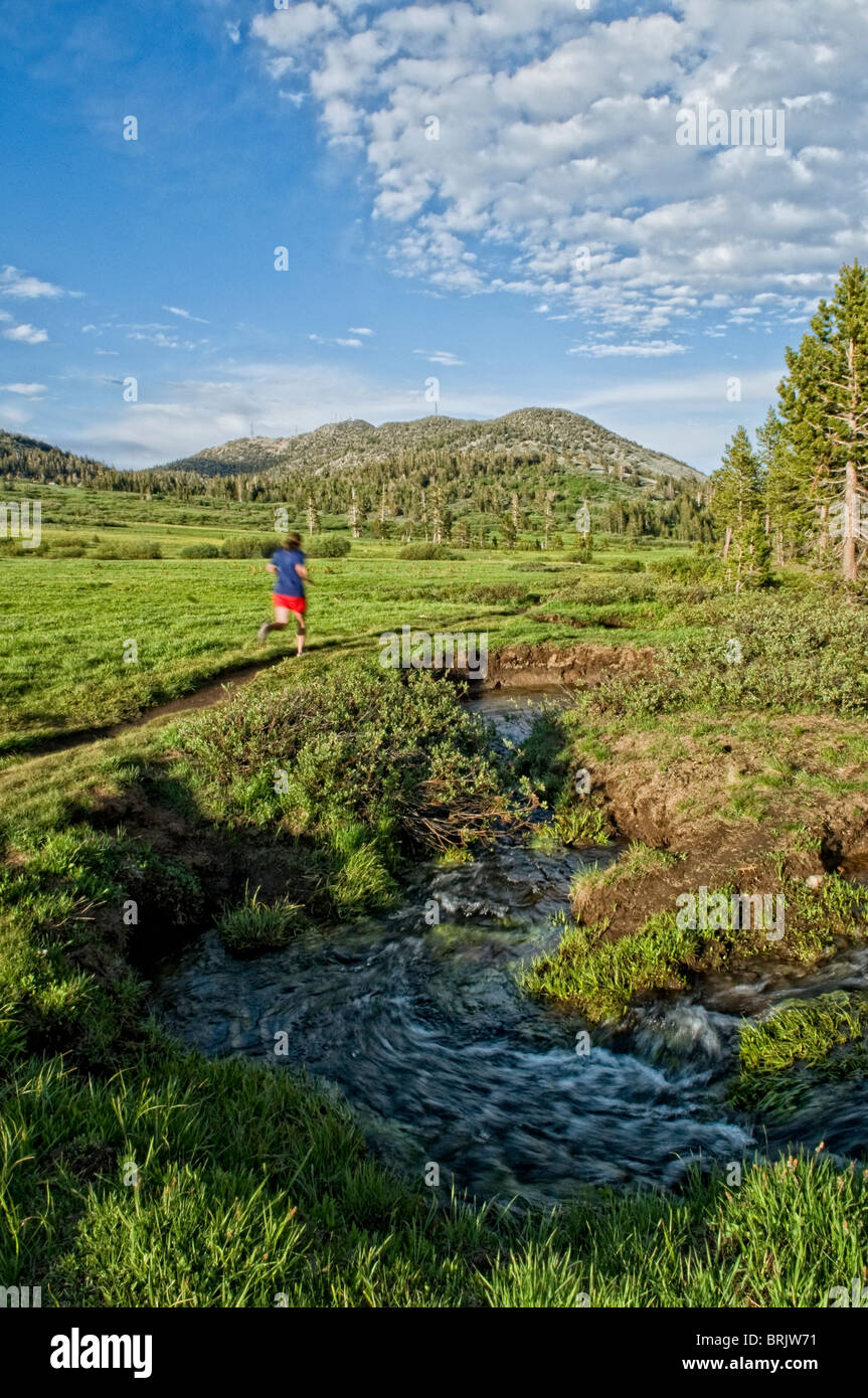 A young woman enjoys the evening light and empty trail during an ...