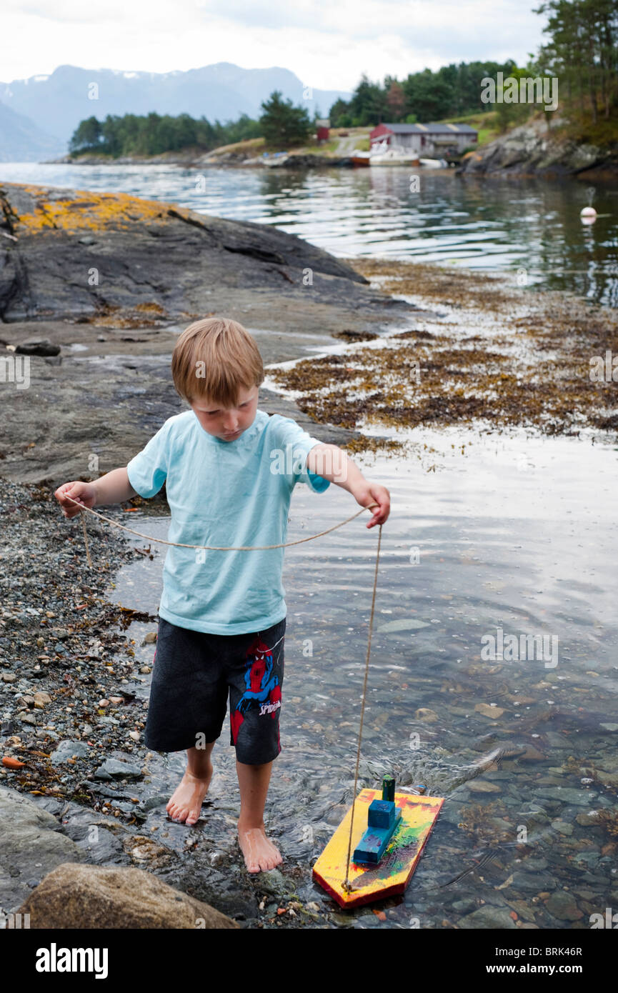 Boy playing with self-made boat by fjord Stock Photo - Alamy
