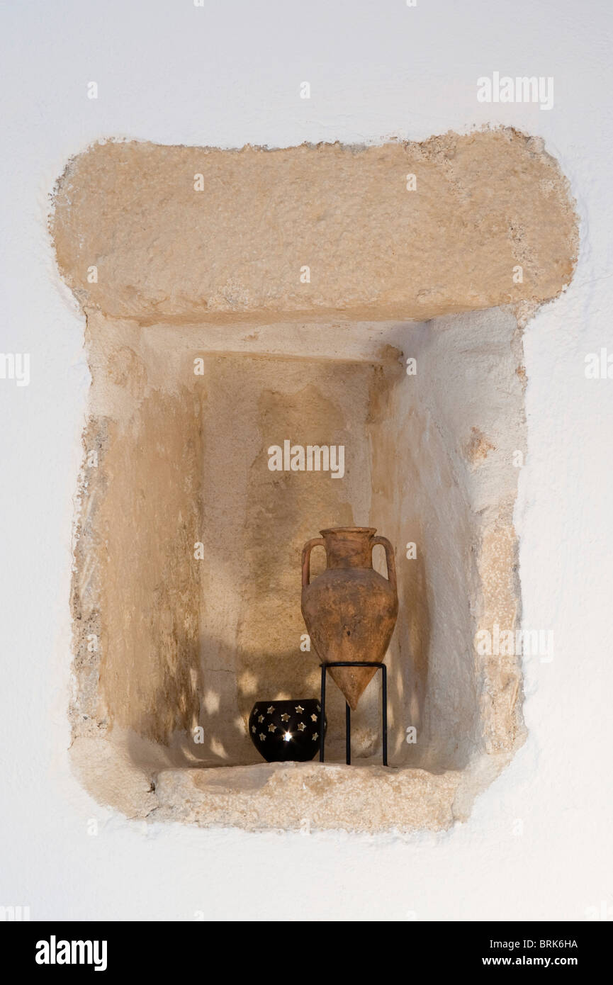 Limestone alcove with Greek urn miniature illuminated by candle in pot ...