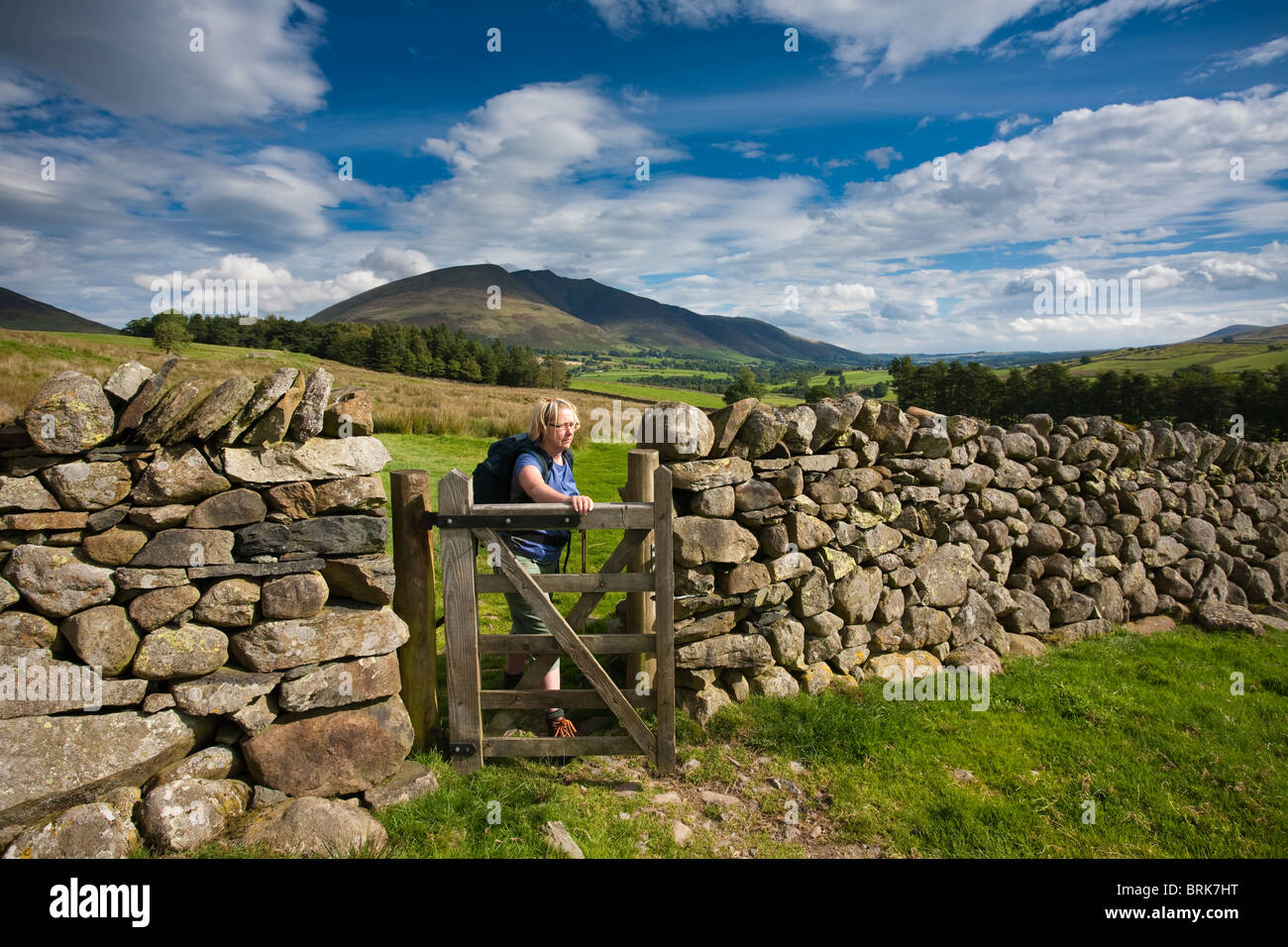 Hiker passing through gate with the distant mass of Blencartha in the ...