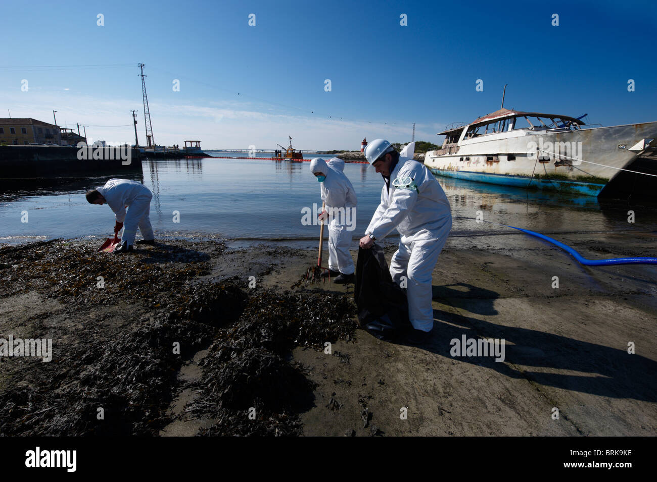 Men in full-body protective clothing and breathing masks clean the dock ...