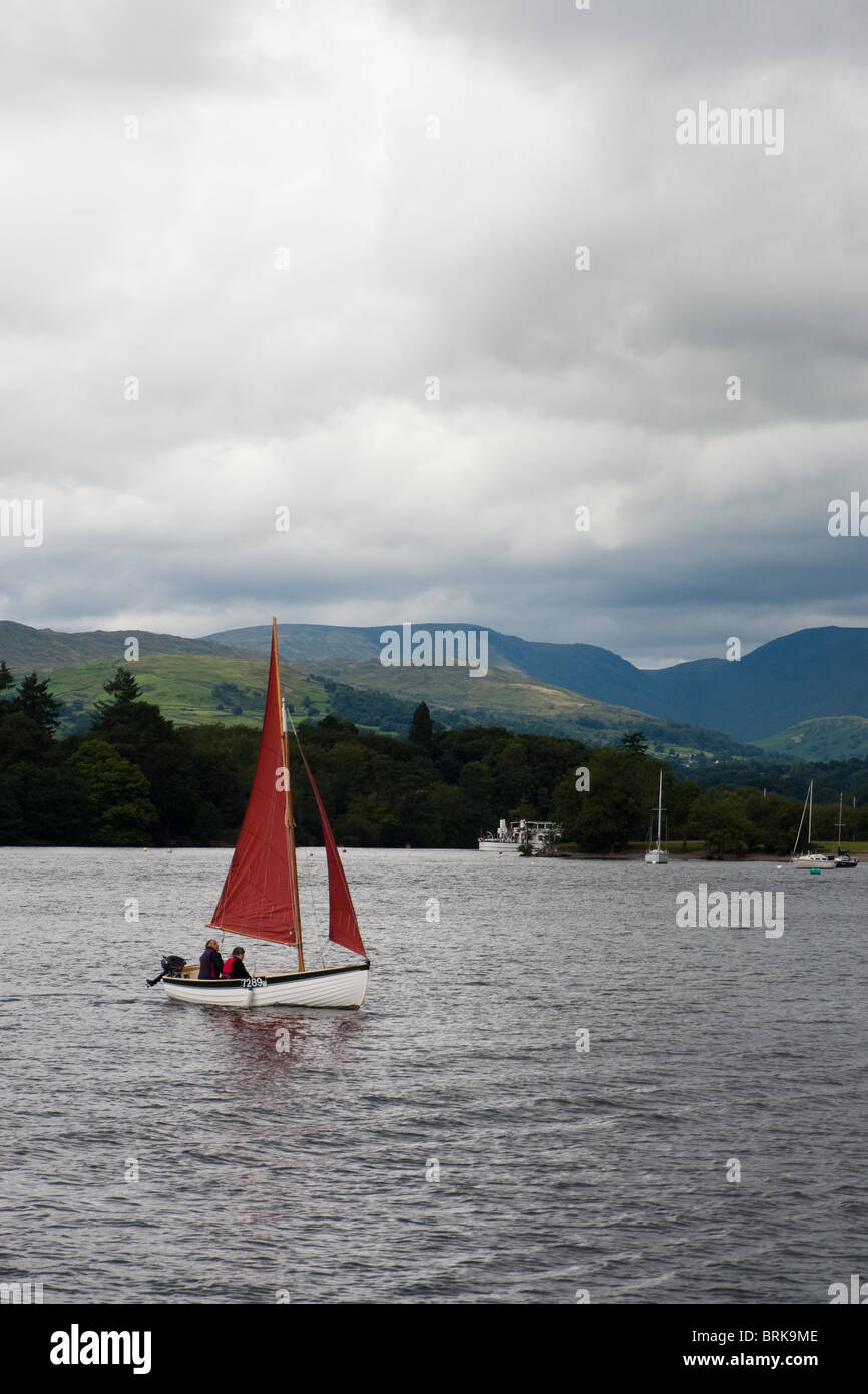 A red sailed boat on Lake Windermere, in the Lake District, Cumbria ...