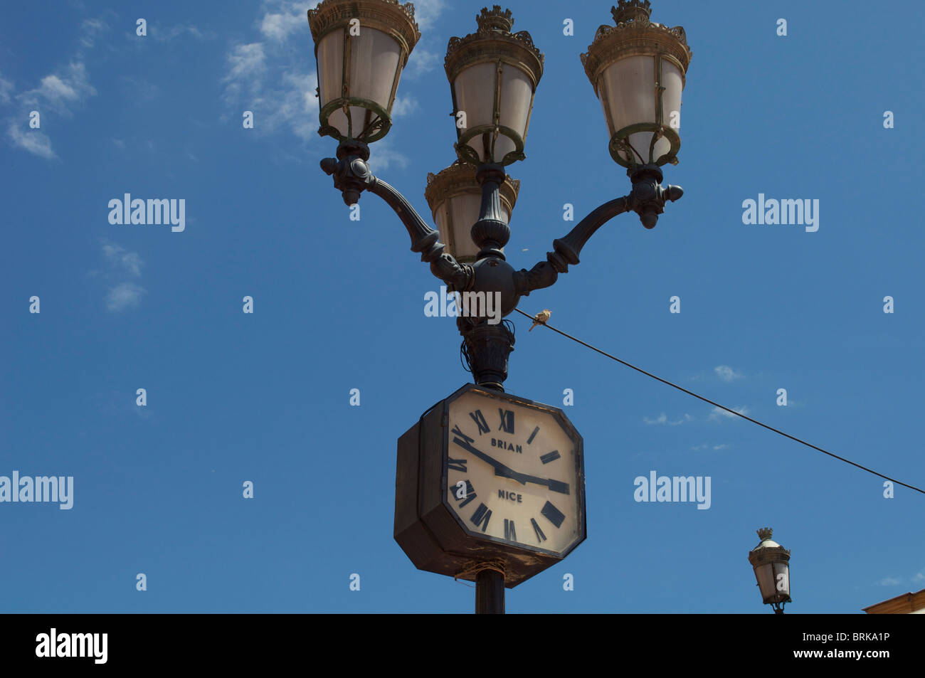 French street clock with lamp posts attached in Nice Stock Photo - Alamy