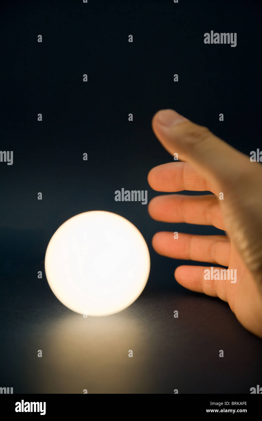 Hand touching a bright ball, Concept of magic Stock Photo - Alamy