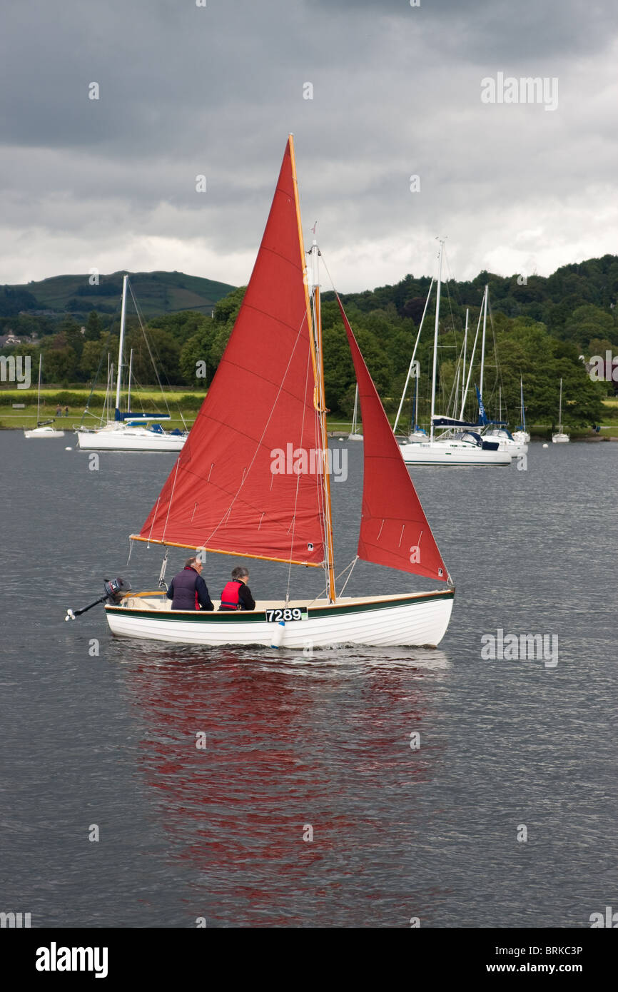 A red sailed boat on Lake Windermere, in the Lake District, Cumbria ...
