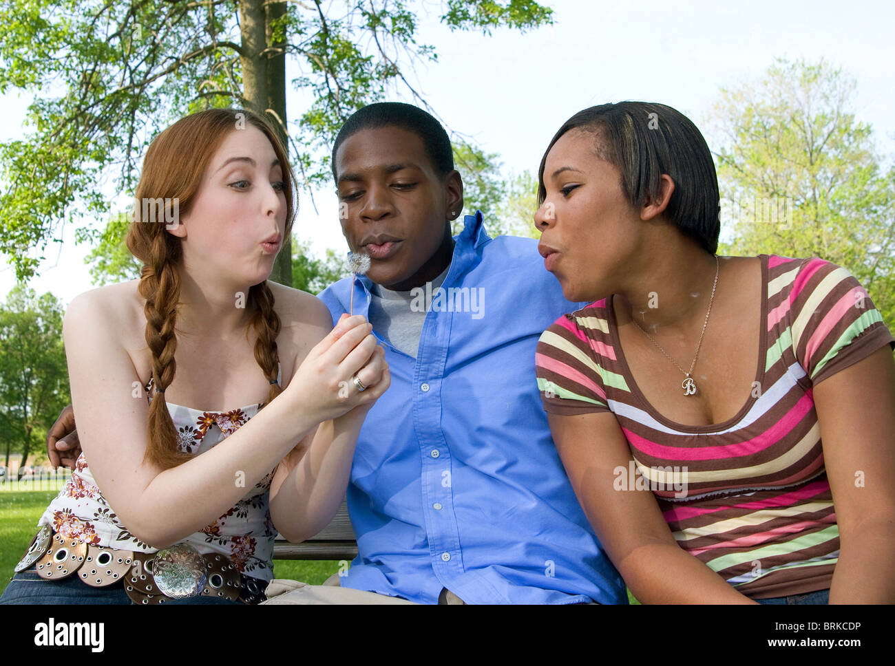 small group of 3 multi-ethnic friends playing in the park and laughing ...
