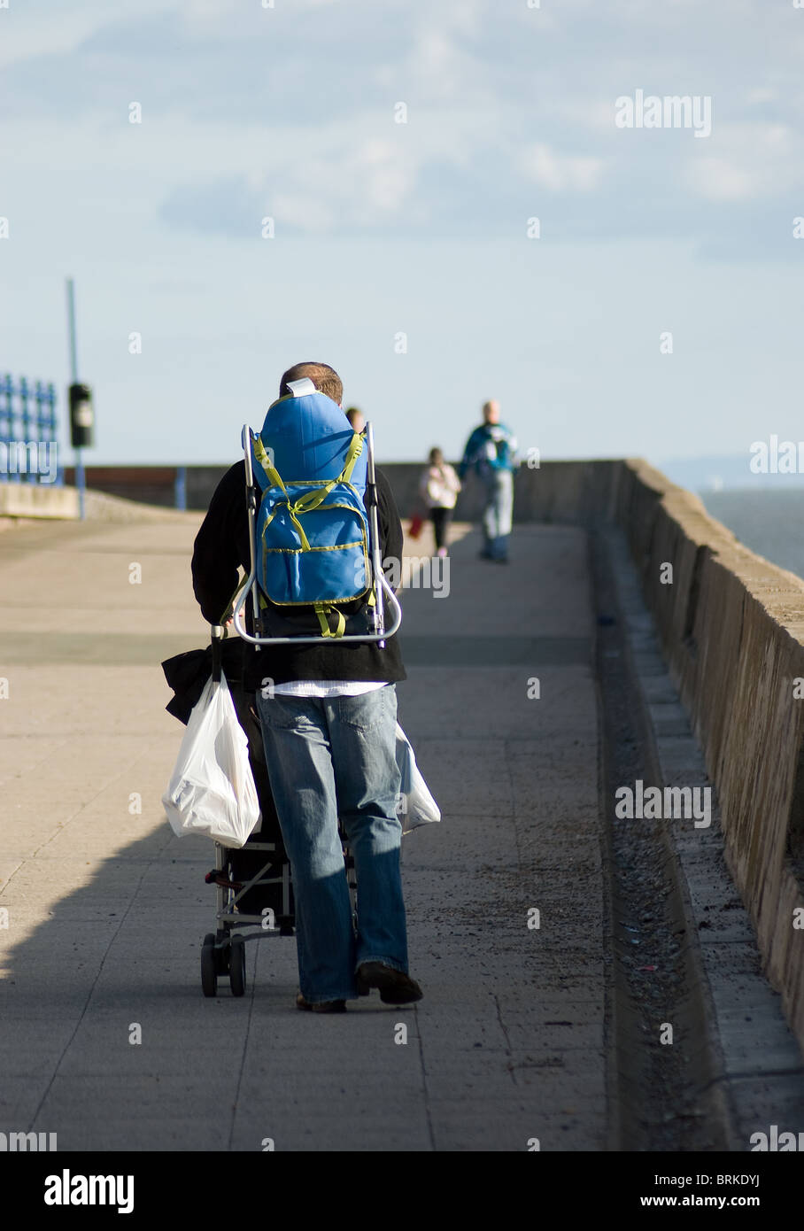 Man pushing a pram along the promenade, Porthcawl, South Wales, UK ...