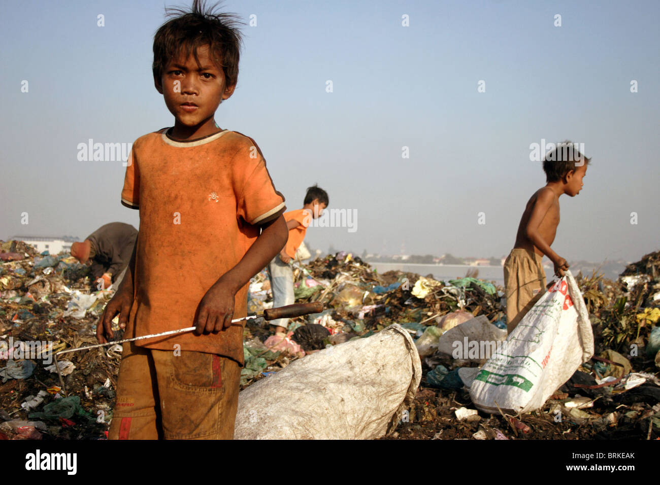 A young child laborer boy looks through garbage for recyclables at ...