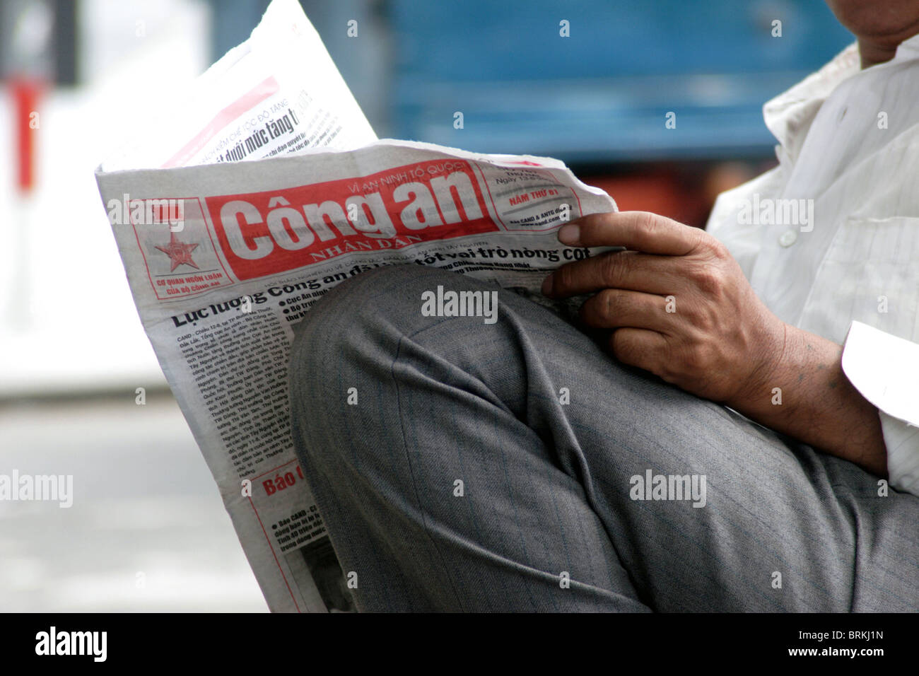 A man is reading The Congan newspaper on a street corner sidewalk in ...