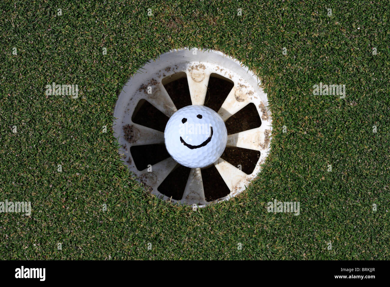 Happy golf ball in a hole Stock Photo - Alamy