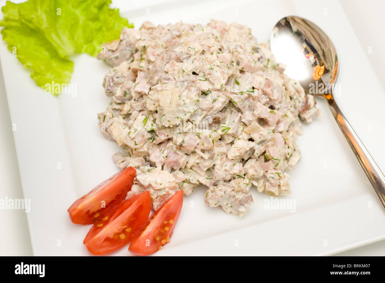 meate salad sauced with mayonnaise is served with tomato pieces and ...