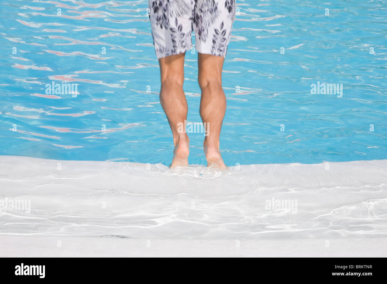 Man diving into a blue pool in black and white shorts Stock Photo - Alamy