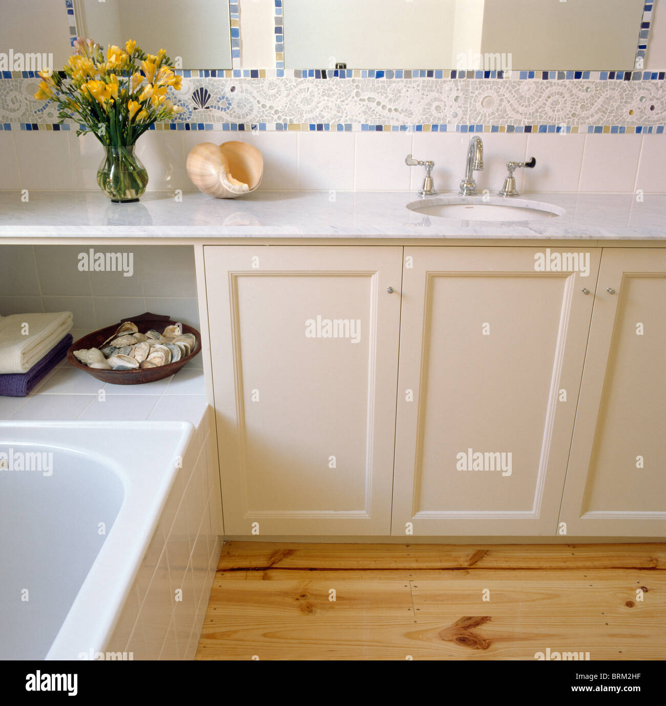 Mosaic tiled border above basin in white marble-topped vanity unit in ...
