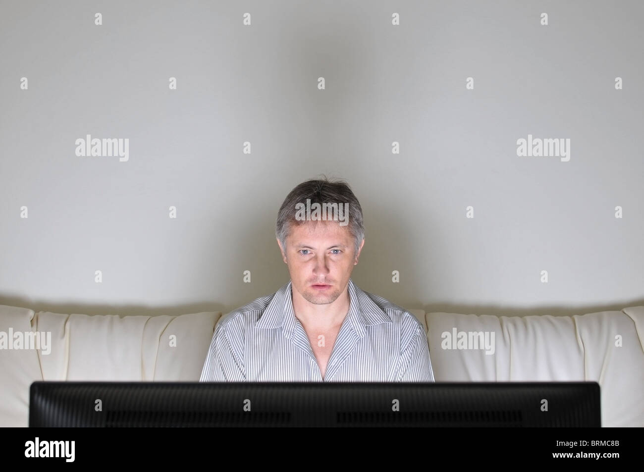 Man alone staring at a television or computer screen Stock Photo - Alamy
