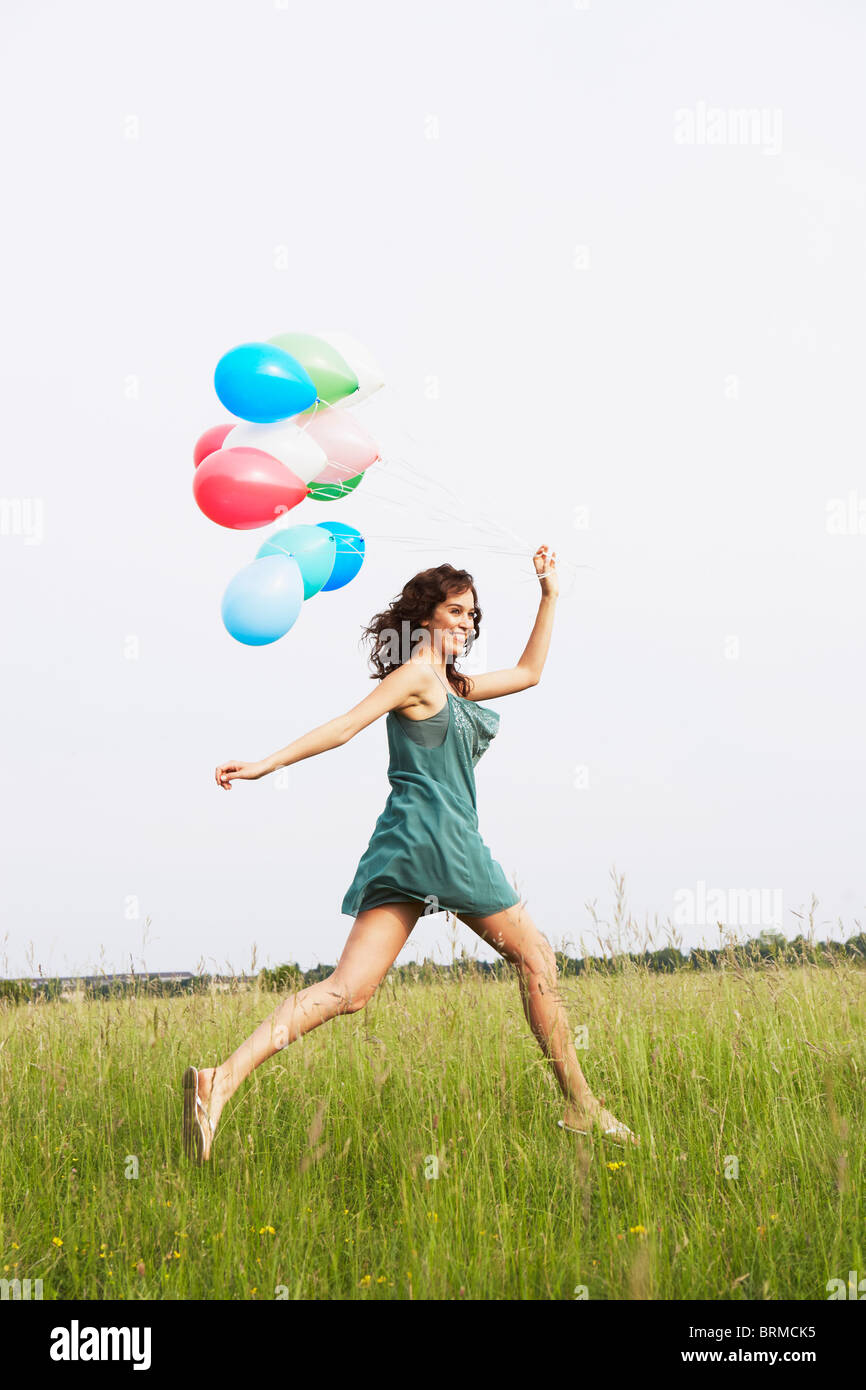 Woman with air balloons jumping Stock Photo - Alamy