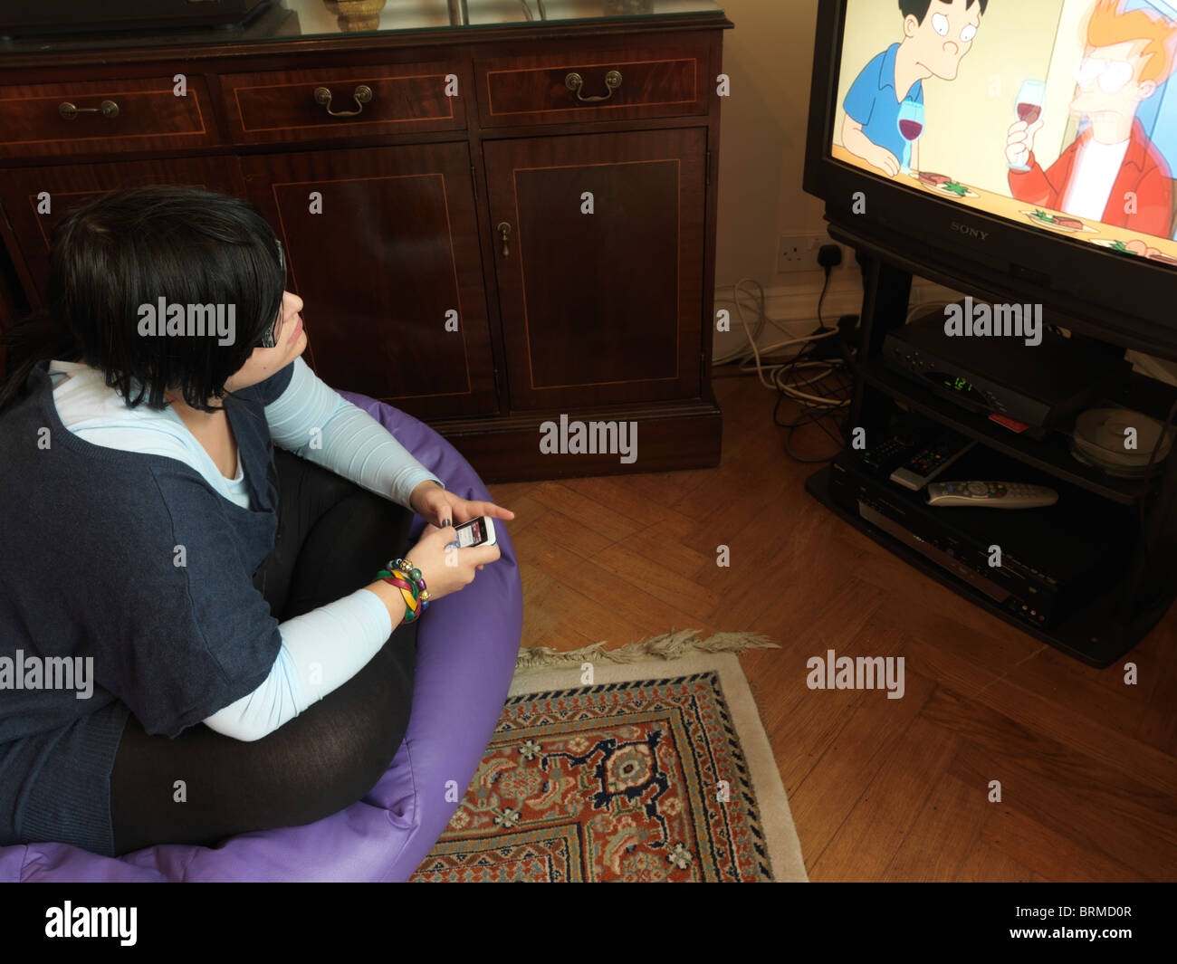 A Teenage Girl Texting on a Mobile Phone While Watching Television ...